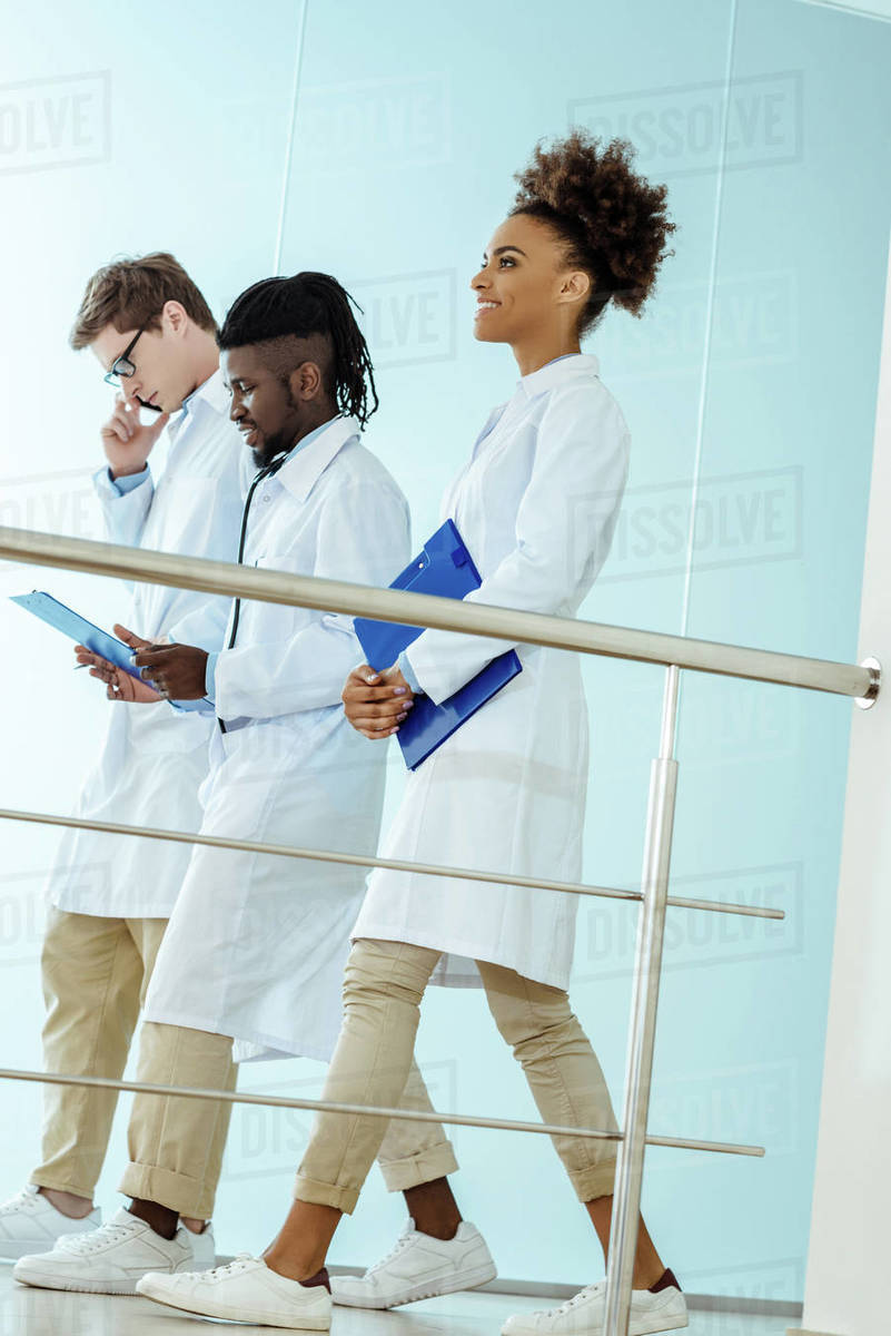 A multiracial group of medical interns walking down the hospital ...