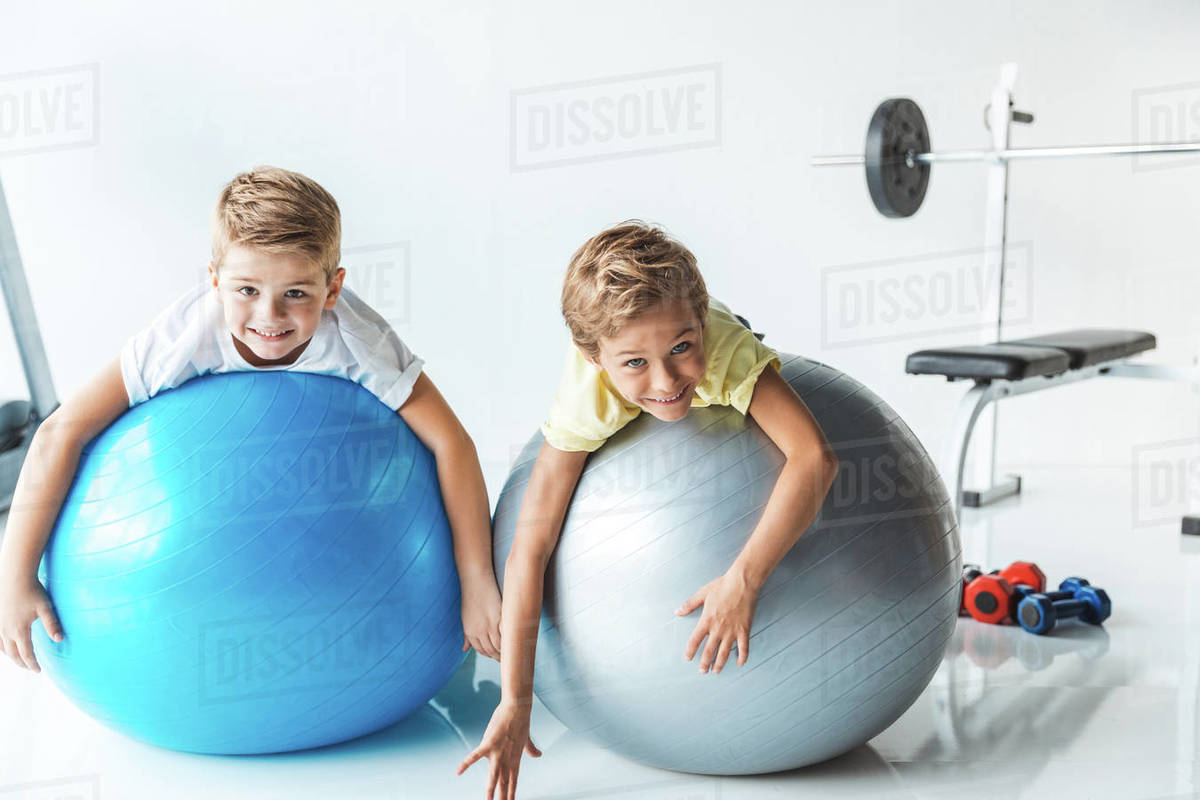 Cute little boys exercising on fitness balls and smiling at camera on ...