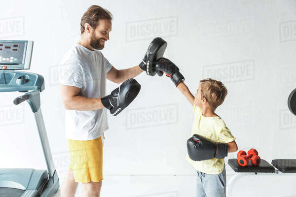 Side view of happy father and little son boxing together - Royalty-free ...