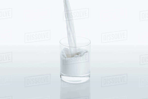 Milk pouring into glass, on white with reflection - Royalty-free Stock ...