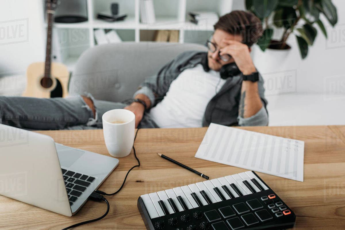 Young tired musician sitting in armchair at workplace - Stock Photo ...