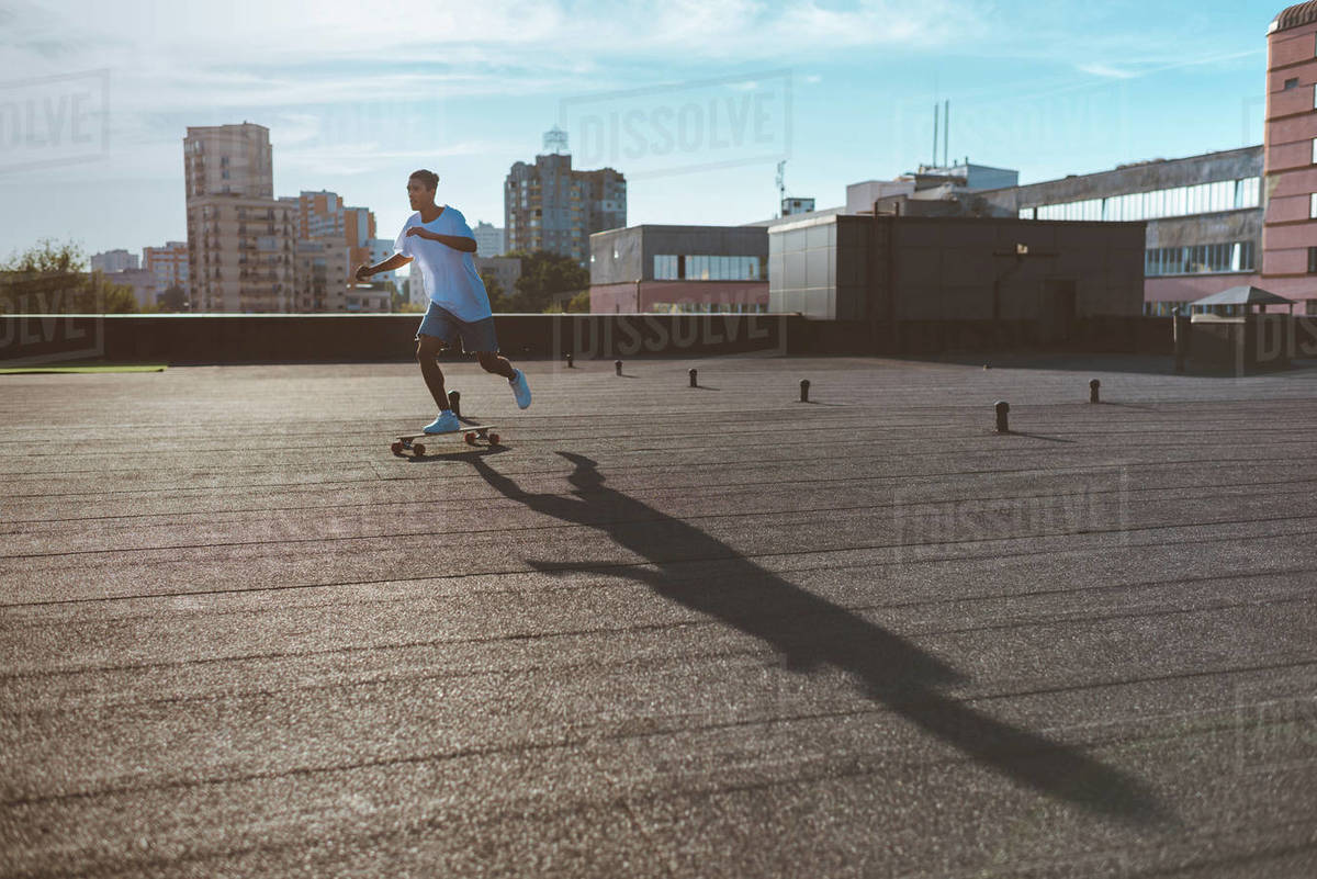 Handsome young man riding skateboard on rooftop - Royalty-free Stock ...