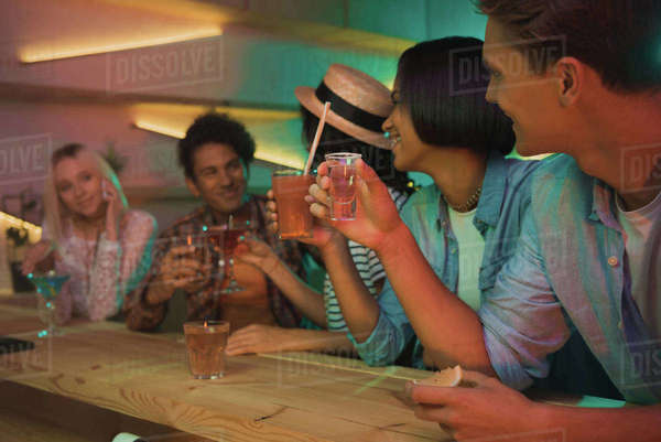 Multiethnic group of friends drinking alcohol cocktails together at ...