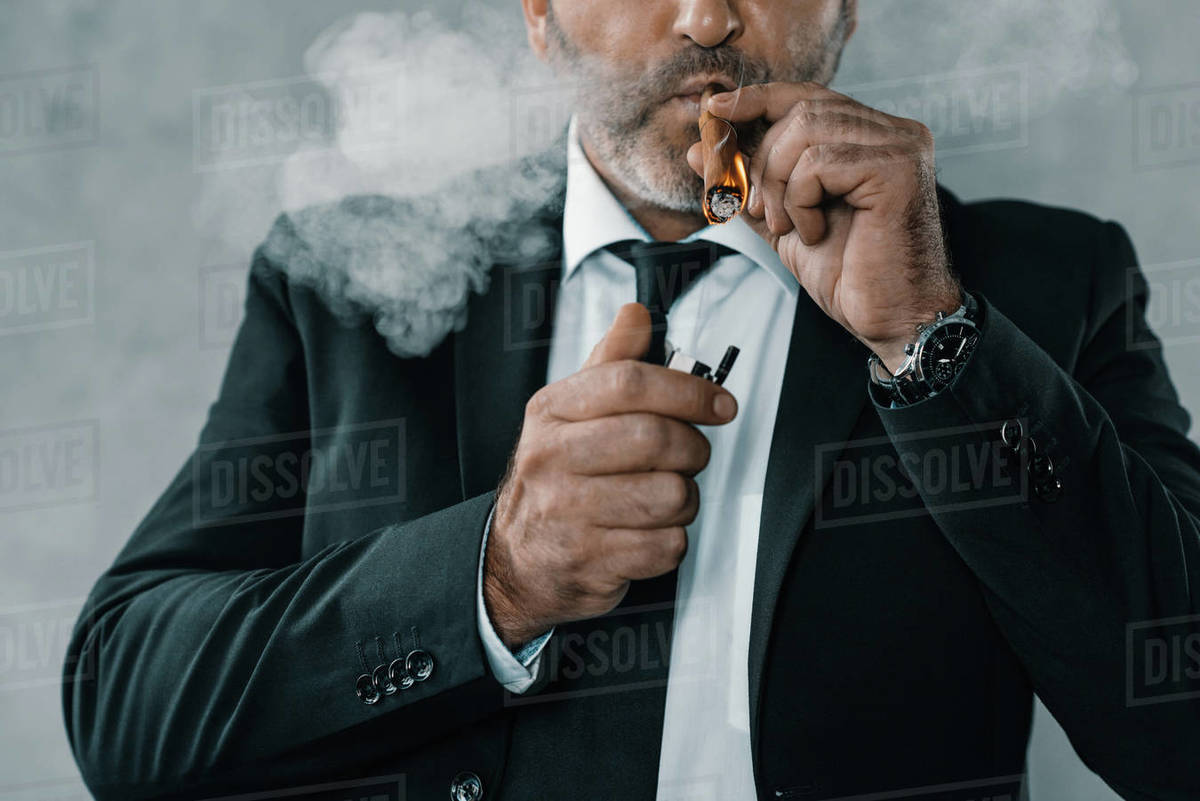 cropped shot of mature businessman in suit smoking cigar - Stock Photo - Dissolve