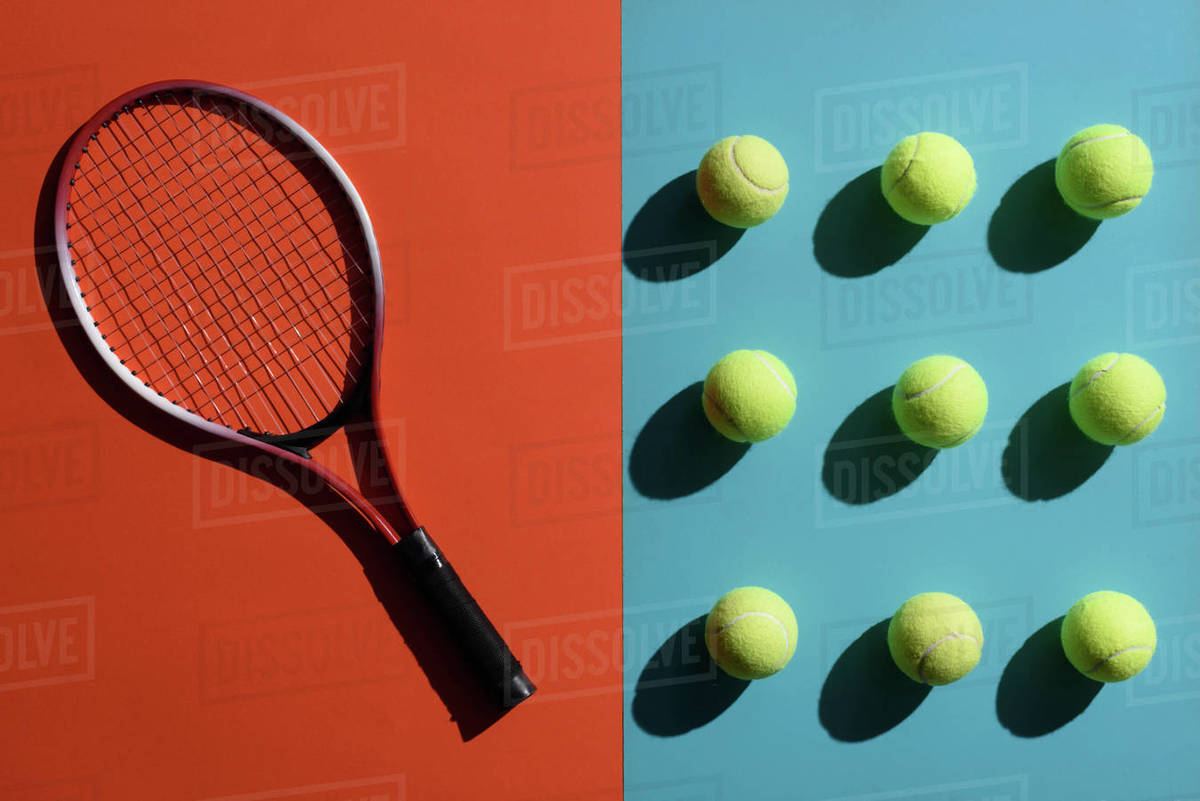 Top view shot of and tennis racket and balls placed on two toned ...