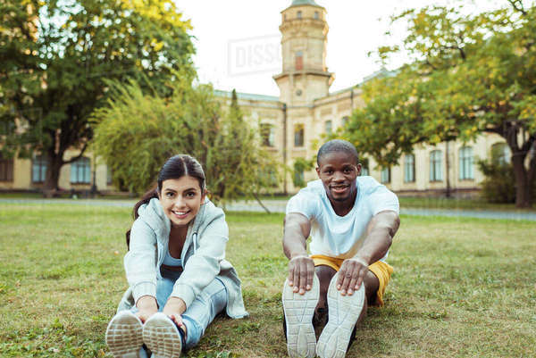 Multicultural couple stretching on a grass at the park - Royalty-free ...