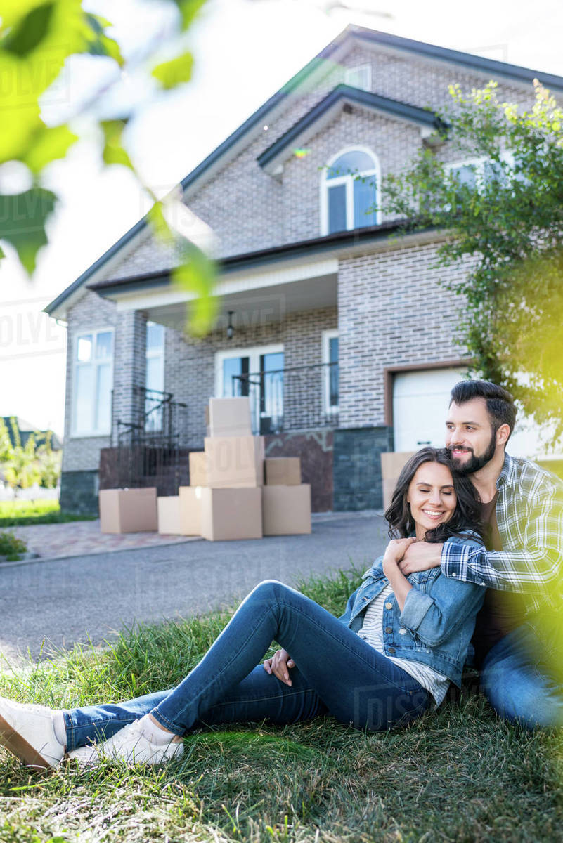 Beautiful couple relaxing on grass in front of new house - Royalty-free ...