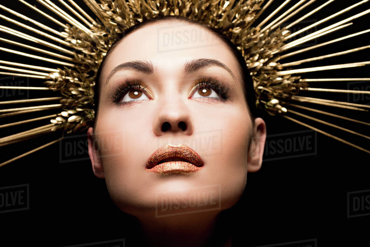 Close up view of attractive woman in golden headpiece looking up ...