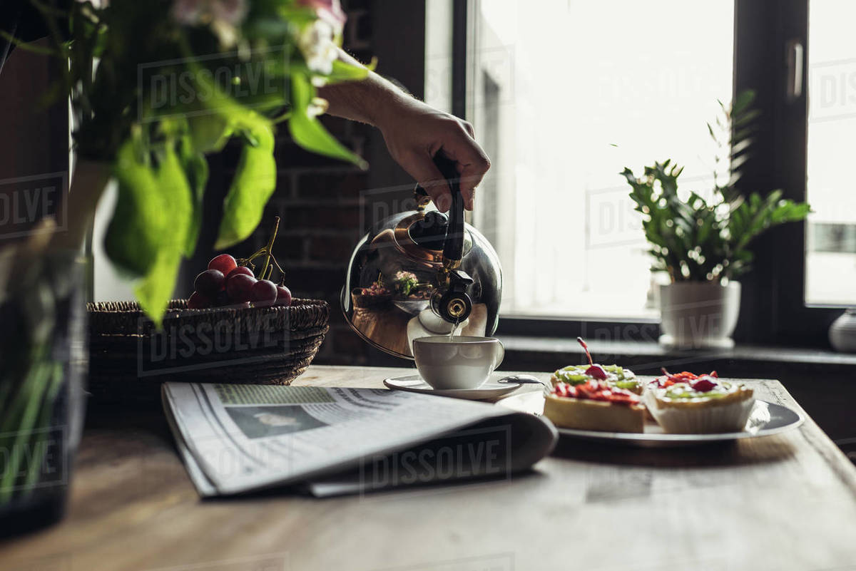 Still life of newspaper, breakfast with cakes and hand pouring hot ...