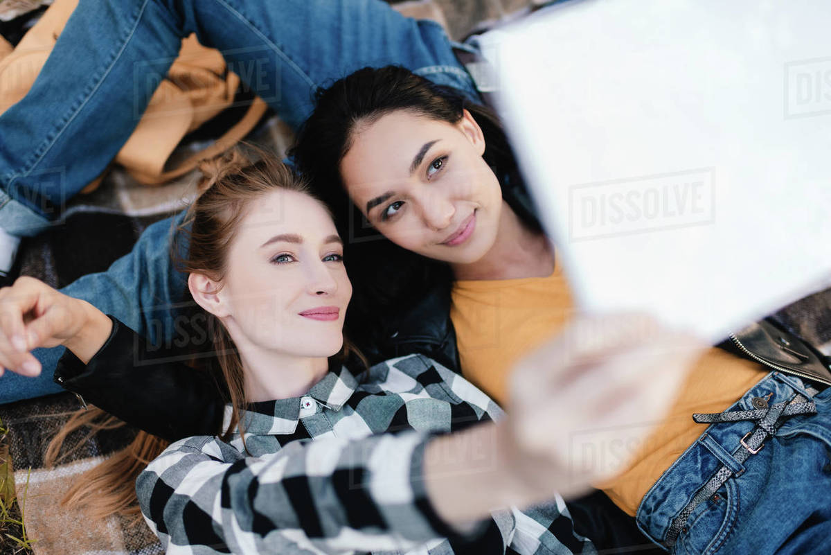 Overhead view of multicultural women taking selfie on tablet together ...