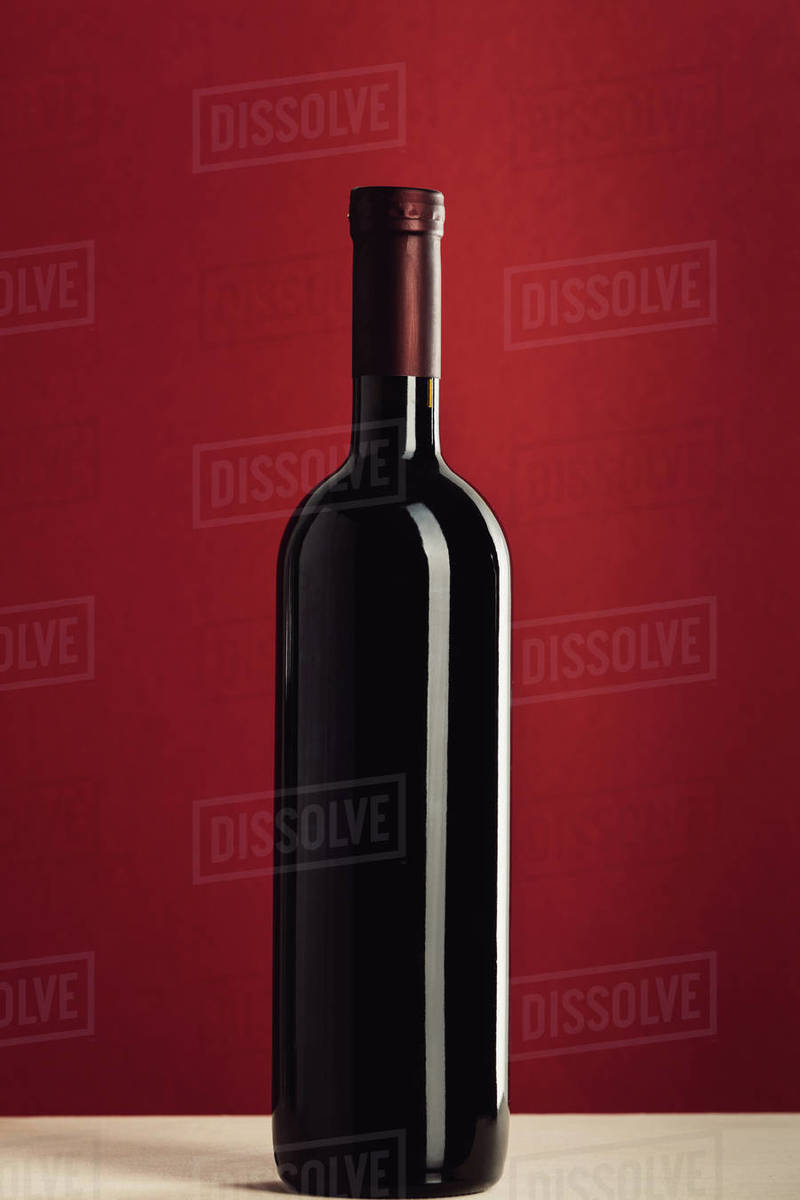 bottle of red wine on tabletop on red - Royalty-free Stock Photo | Dissolve