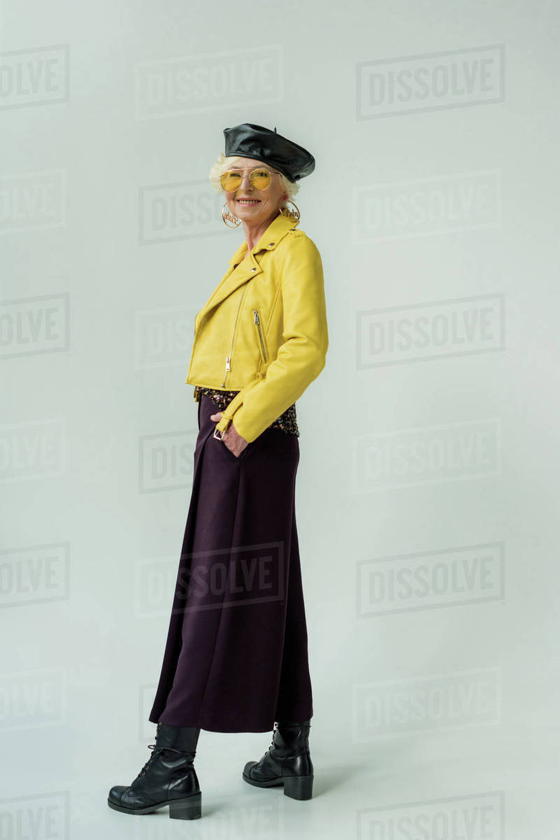 fashionable senior woman in yellow leather jacket and yellow sunglasses ...