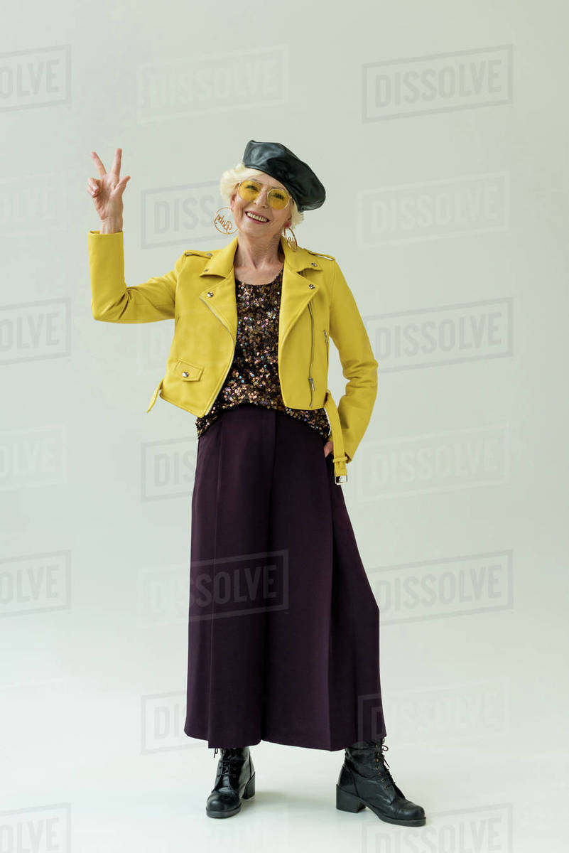 fashionable senior woman in yellow leather jacket and yellow sunglasses ...
