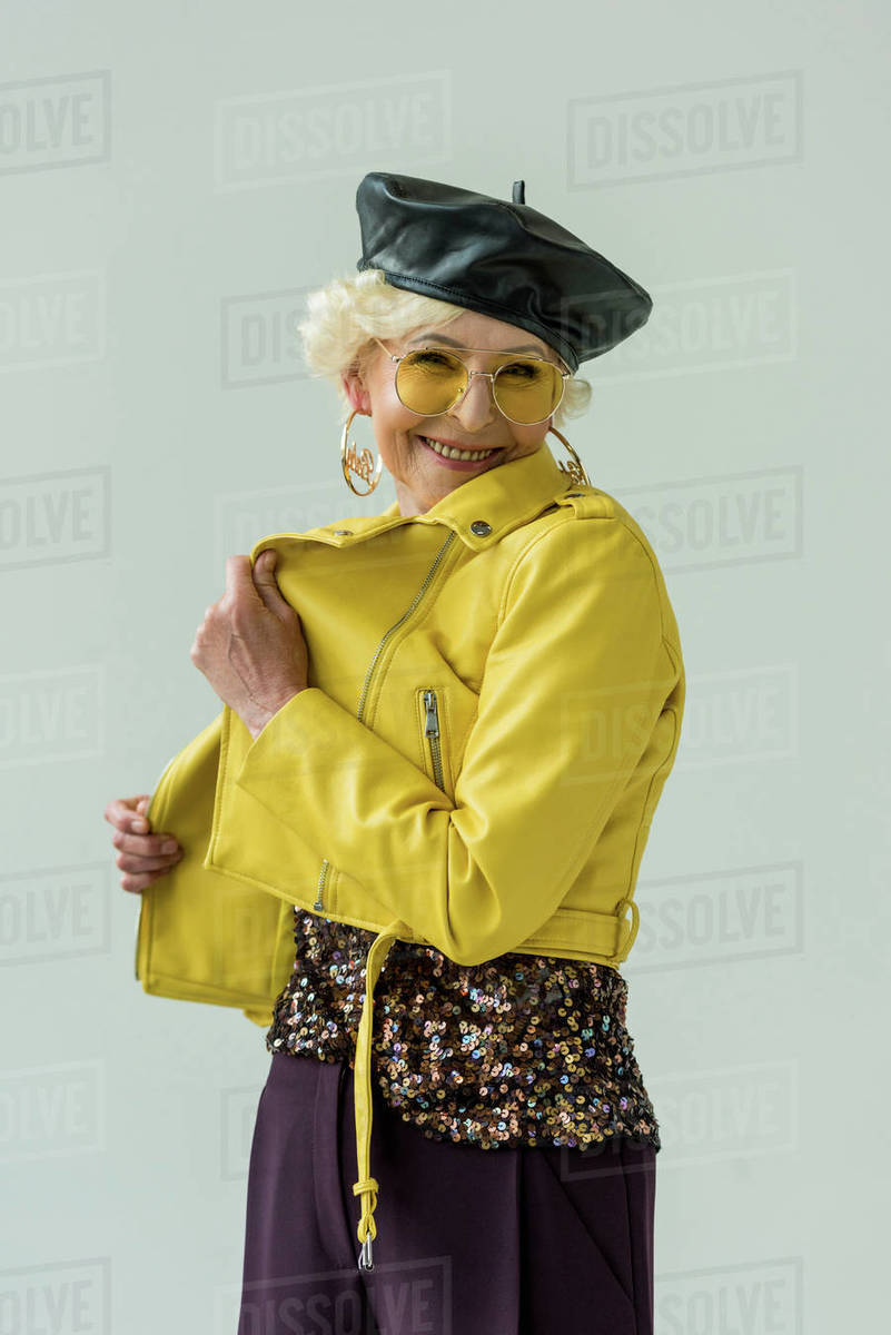stylish senior woman in yellow leather jacket and beret, isolated on ...