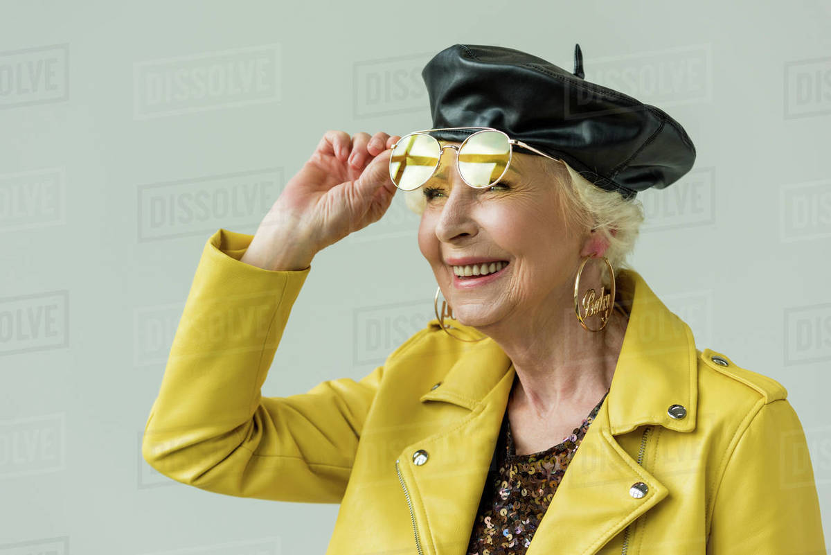 stylish senior woman in yellow leather jacket and yellow sunglasses ...