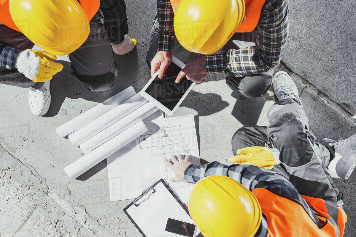 Top view of three construction workers sitting on concrete and ...