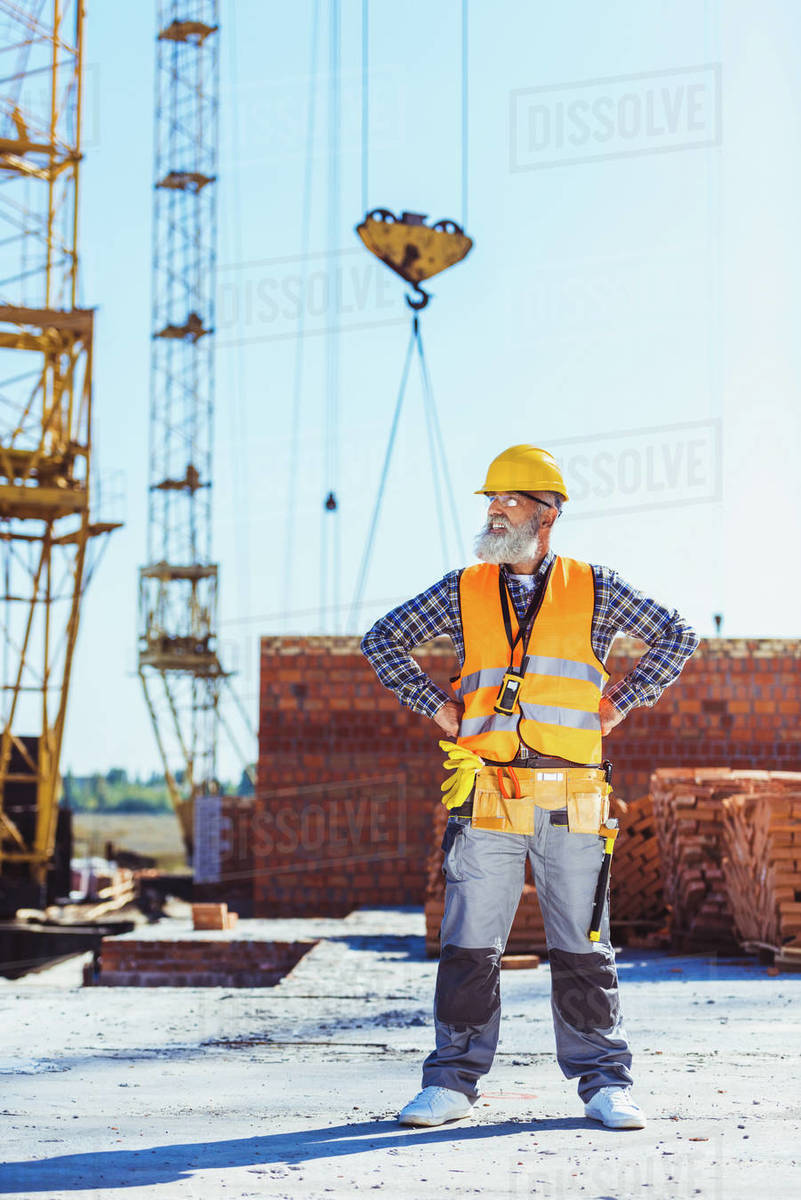 Construction worker in reflective vest and hardhat standing with hands ...