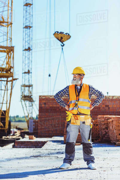 Construction worker in reflective vest and hardhat standing with hands ...