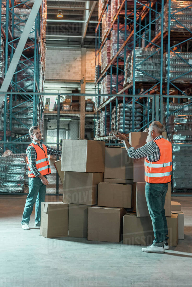 Full length view of two warehouse workers working with boxes in ...