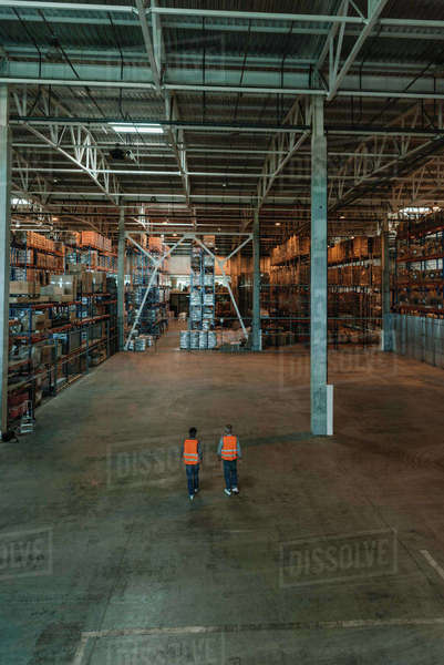 Back view of two male warehouse workers walking in storehouse - Royalty ...