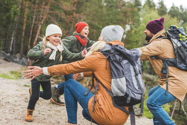 Side view of happy kids running into parents hands in autumn forest ...