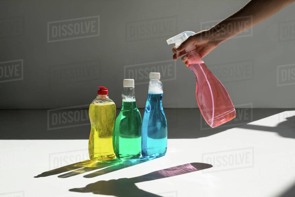 Cropped shot of human hand holding spray bottle and various cleaning ...