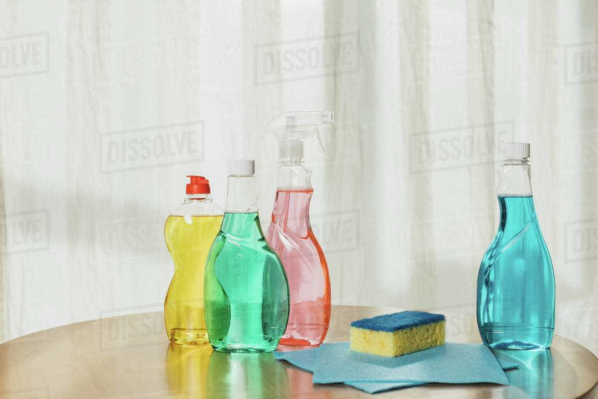 Plastic bottles with colorful cleaning products, sponge and rags on ...