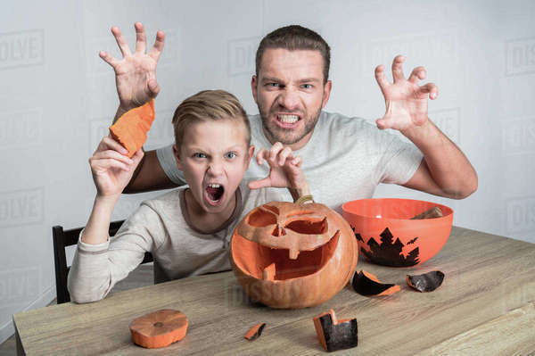 Scary father and son doing jack-o-lantern together and looking at ...