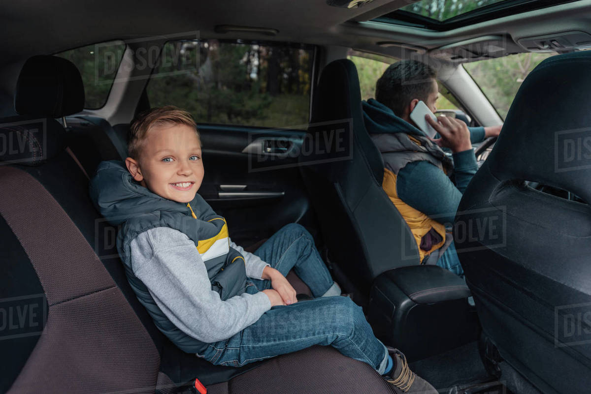 Adorable little boy smiling at camera while father talking on ...