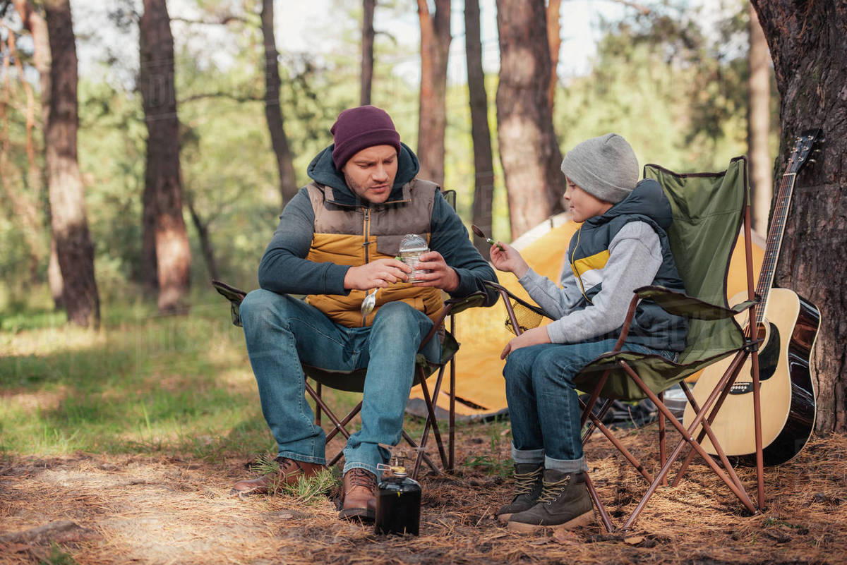 Father and son eating beans from can in forest - Royalty-free Stock ...