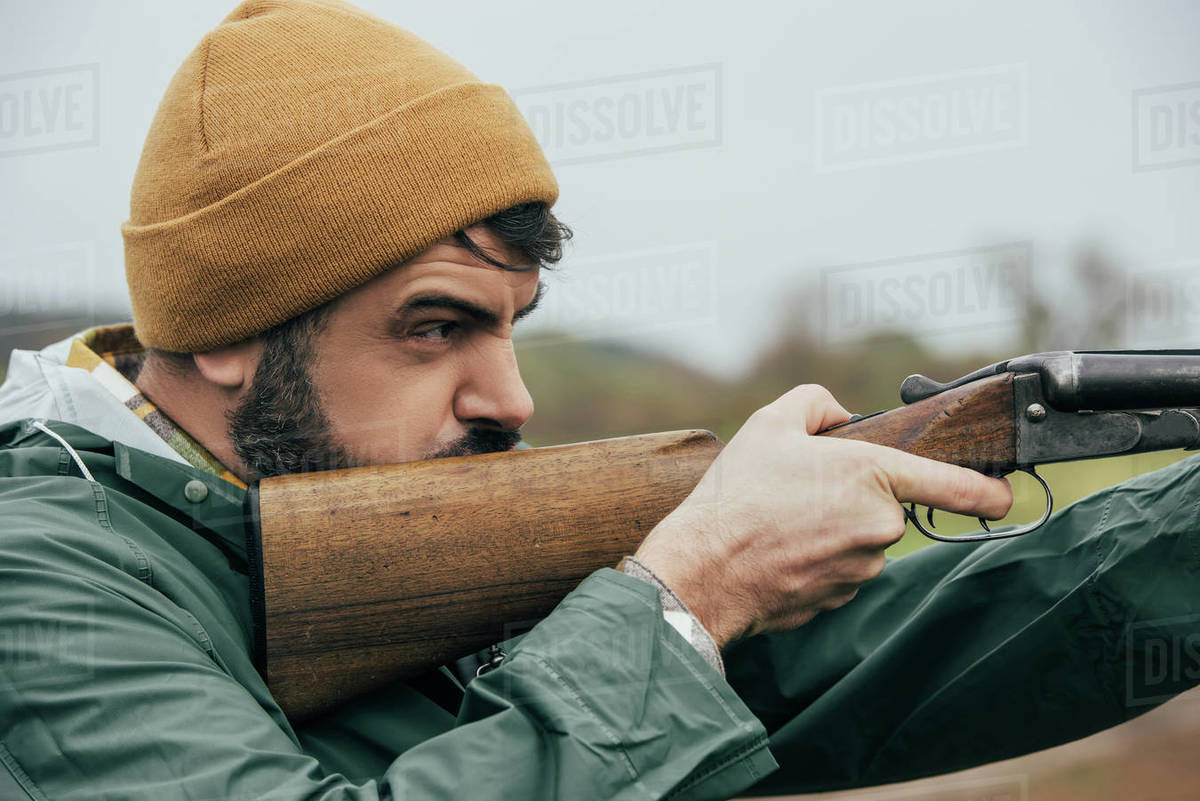 Handsome man aiming with gun on a nature - Stock Photo - Dissolve