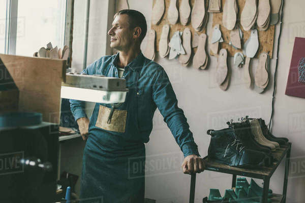 Thoughtful shoemaker in working clothes and apron in workshop - Royalty ...