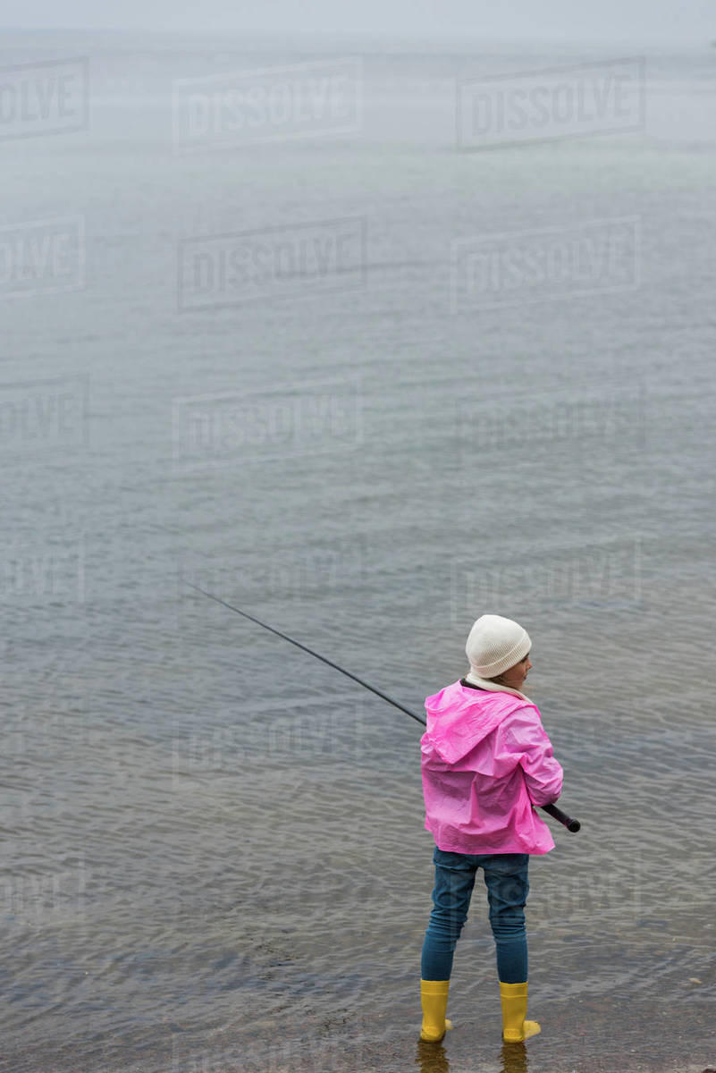 little girl in raincoat and boots fishing alone - Royalty-free Stock ...