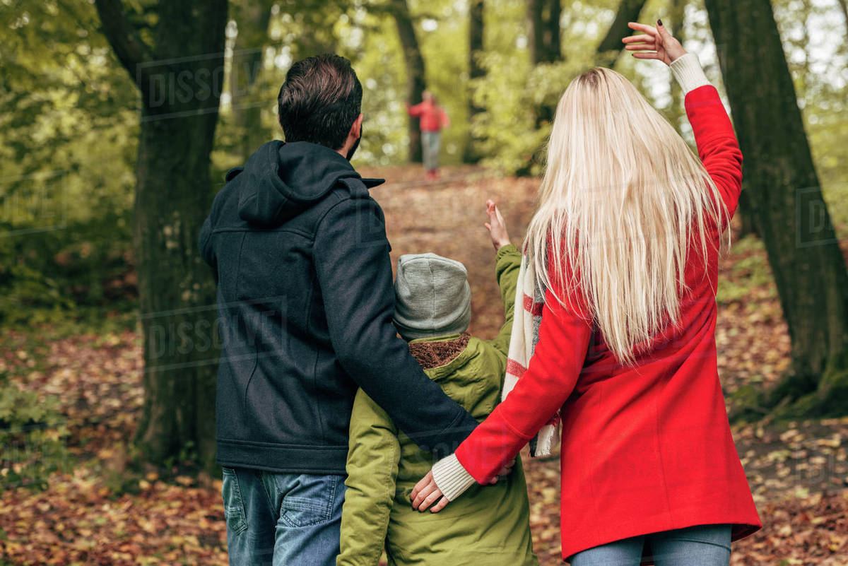 back view of parents with cute little son standing together and looking ...