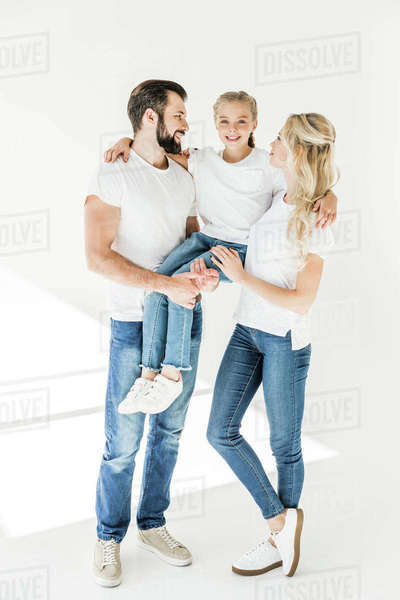 Happy parents looking at adorable smiling daughter isolated on white ...