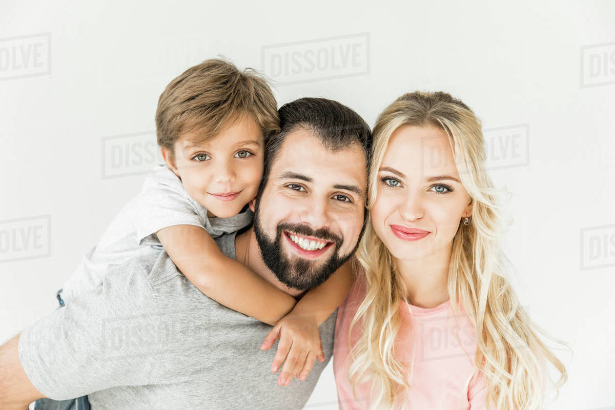 Happy young family with one child smiling at camera isolated on white ...