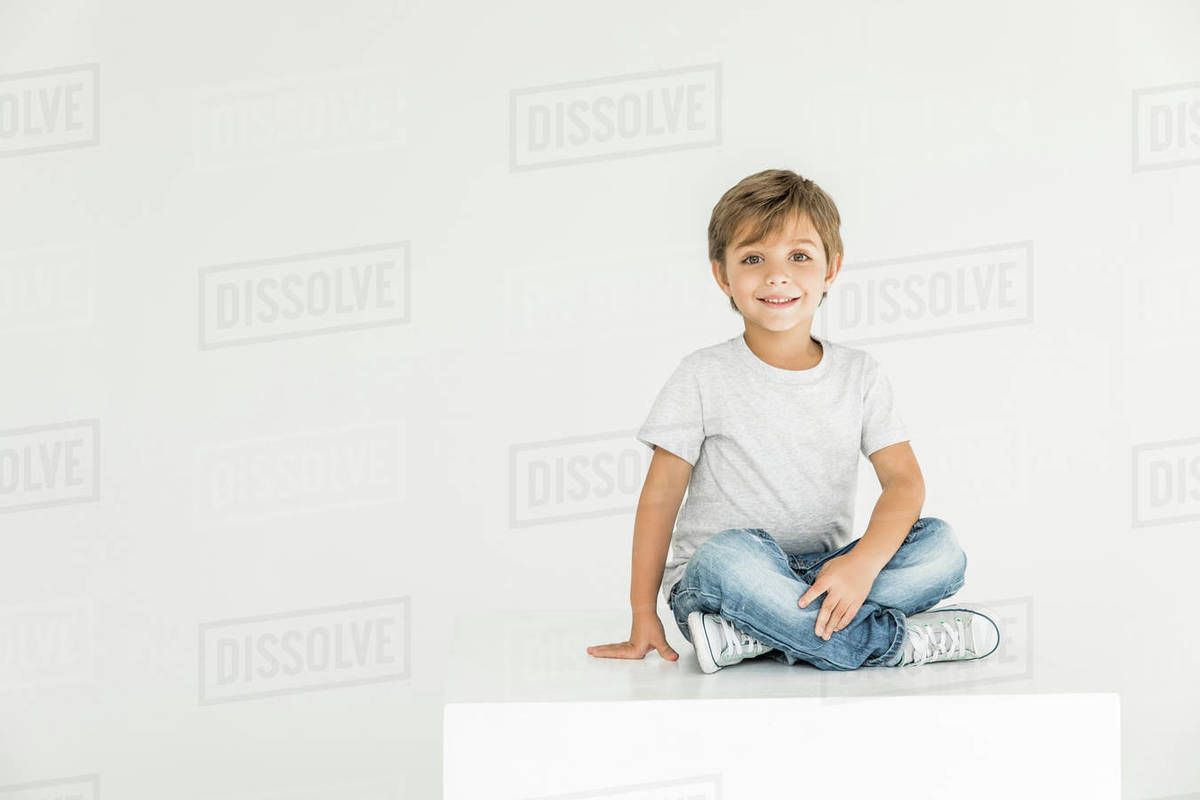 Adorable little boy sitting and smiling at camera isolated on white ...