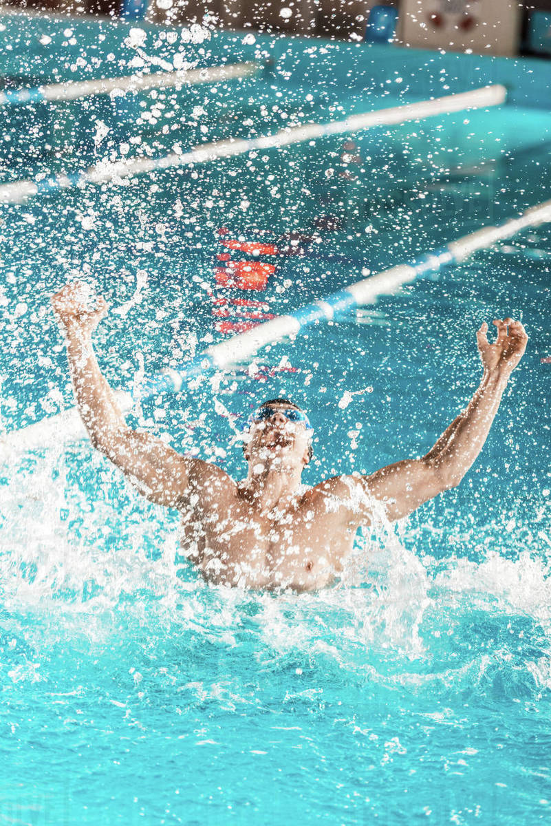 Handsome winning muscular swimmer in competition swimming pool ...