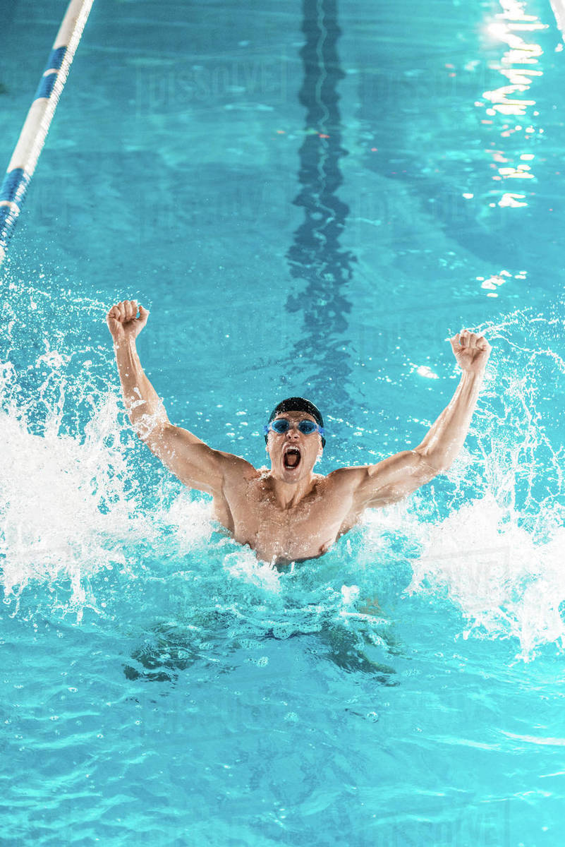 Excited swimmer gesturing and making splash in competition swimming ...