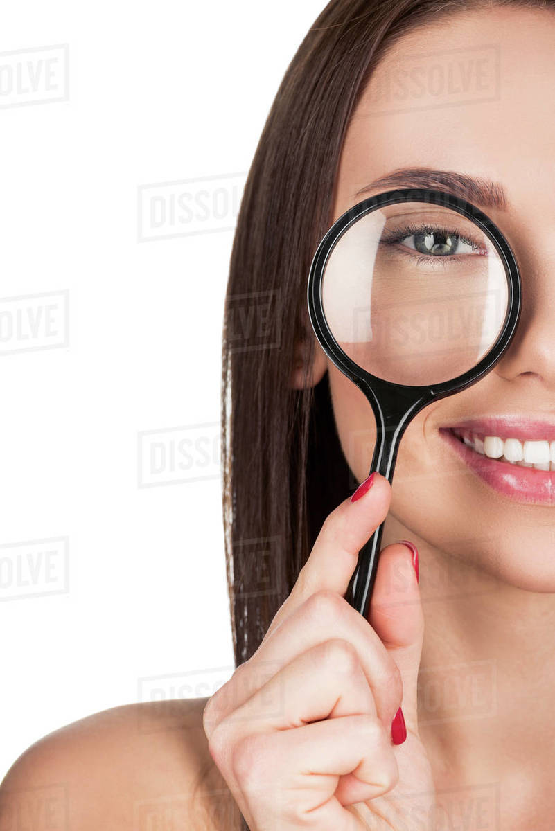 Close-up shot of young woman looking at camera with magnifying glass ...