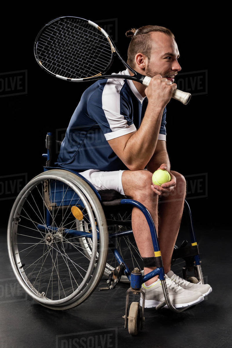 Disabled young sportsman in wheelchair holding tennis racquet with ball ...