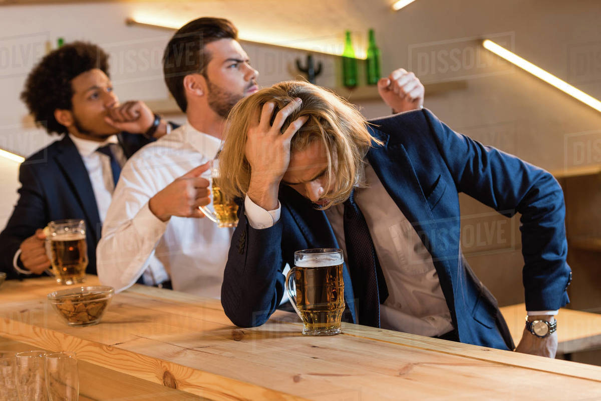 Disappointed multiethnic businessmen drinking beer in bar - Royalty ...
