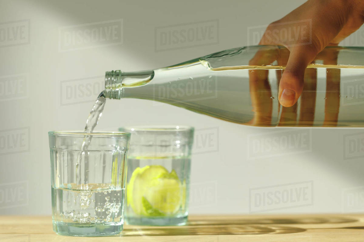 Cropped image of woman pouring water into transparent glass - Royalty-free Stock Photo | Dissolve