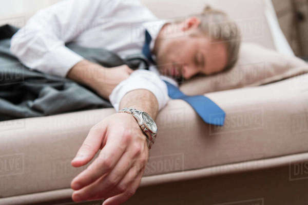 Tired businessman sleeping on a sofa in the living room and covering ...