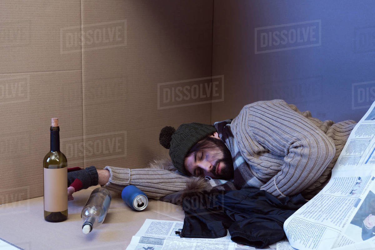 Homeless man sleeping on newspapers in cardboard box - Royalty-free ...