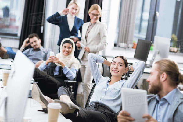 Selective focus of young smiling business people at workplaces in ...