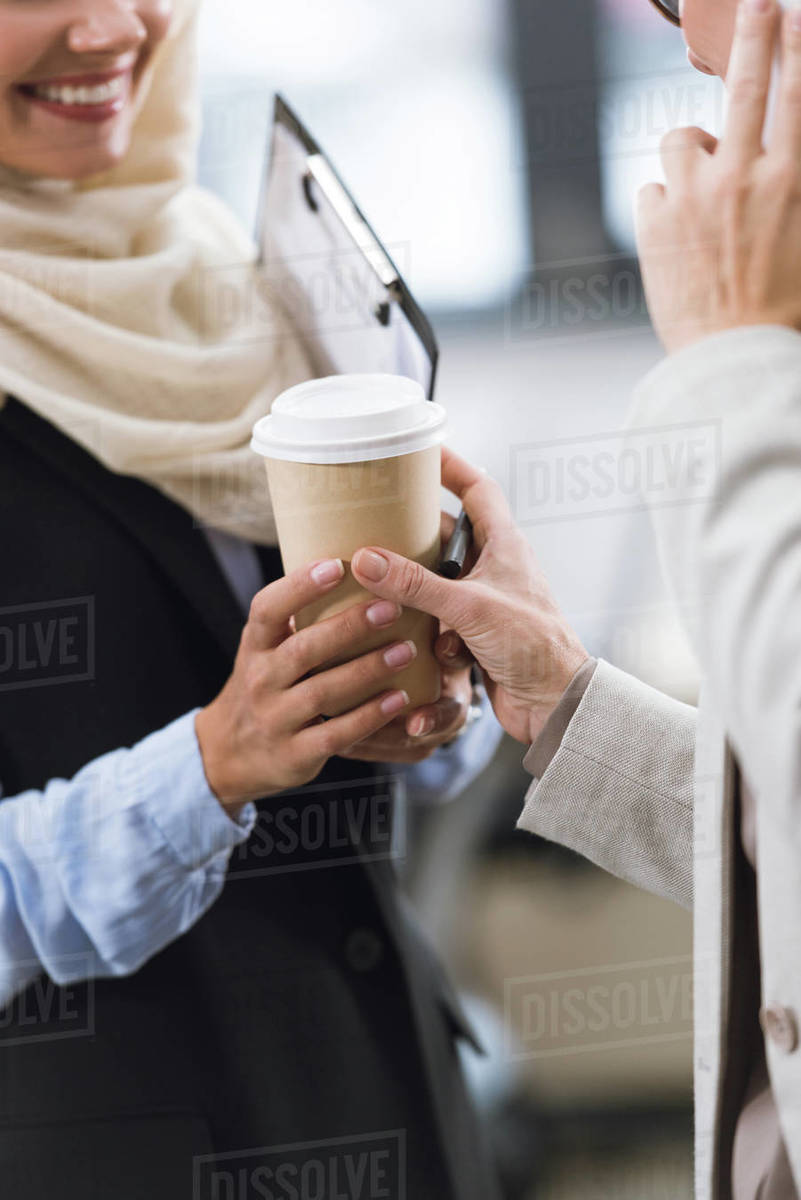 Partial view of smiling businesswoman giving coffee to colleague at ...