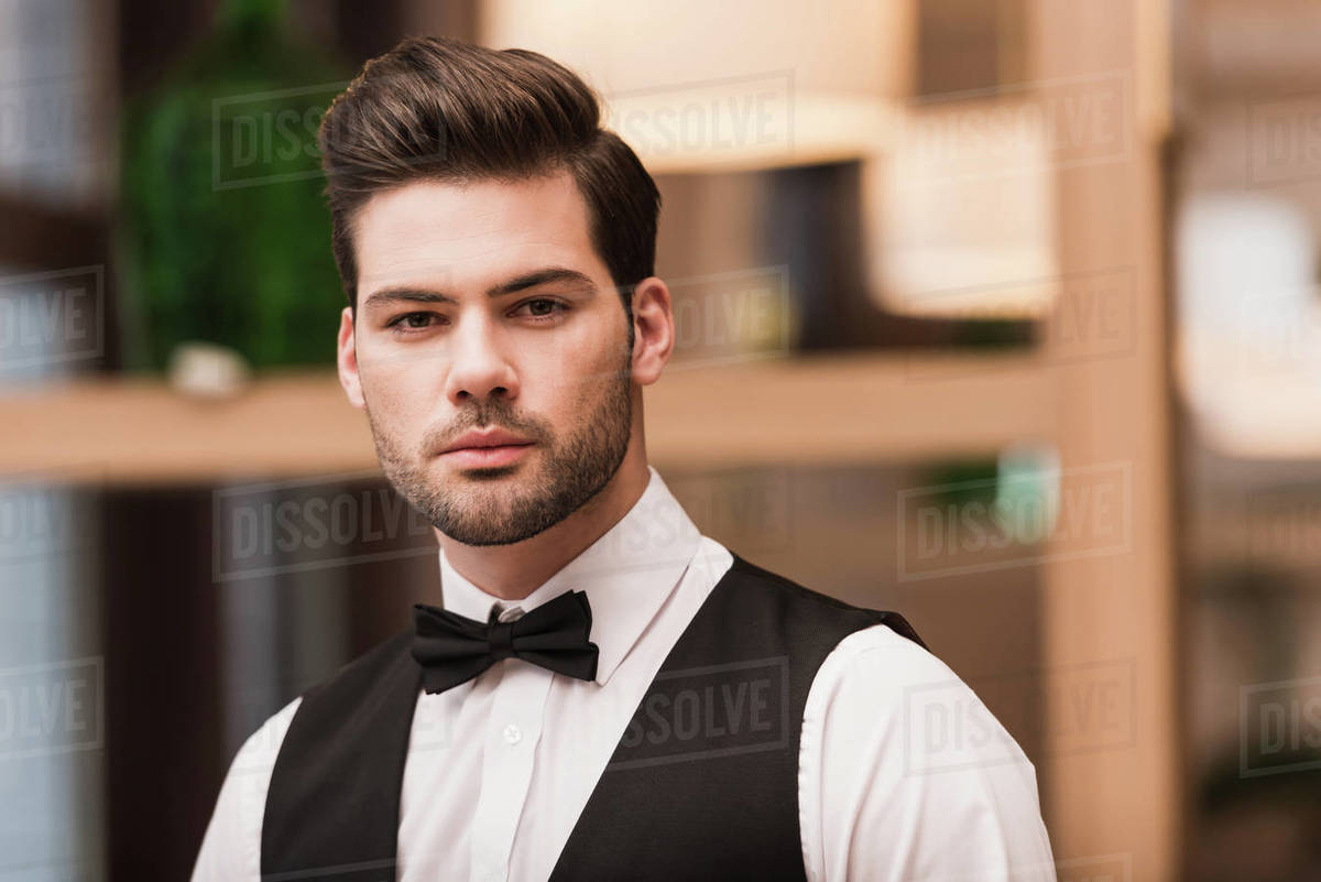 Portrait of handsome waiter looking at camera - Stock Photo - Dissolve