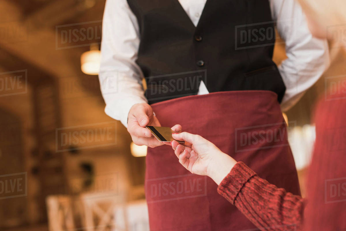Cropped image of Customer giving credit card to waiter to pay for lunch ...