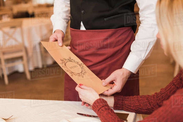 Cropped image of Waiter giving menu to female customer at the ...